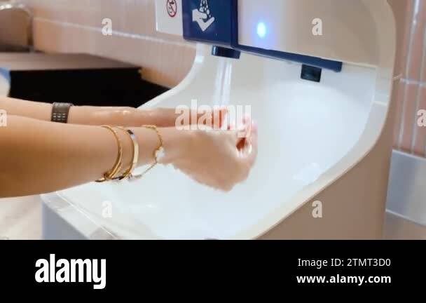 A person washes their hands using a touchless machine, activated by ...