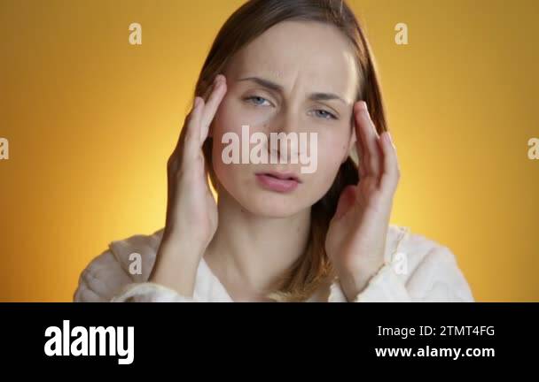Young sad woman with headache massaging her temples with circular ...