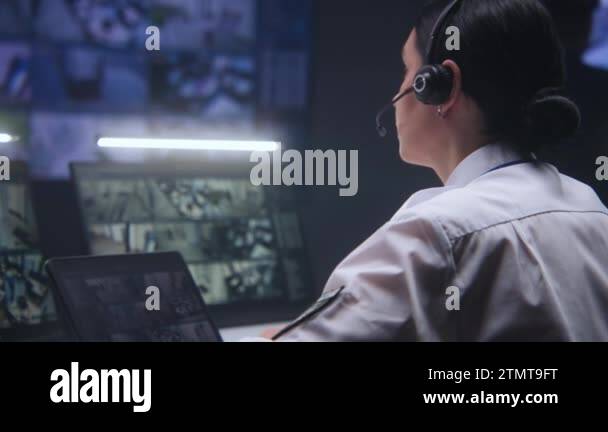 Female operator in headset zooms and monitors security cameras with AI ...