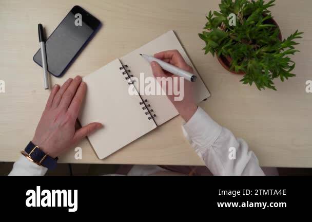 A woman draws a question mark in a notebook. A woman draws a question ...