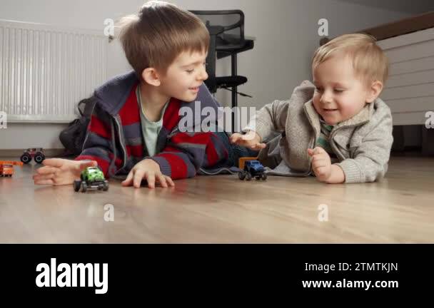 Baby boy with older brother having toy car race on floor. Children ...
