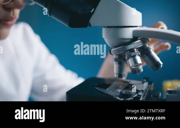 Female studying DNA mutations by looking and rotating microscope in ...