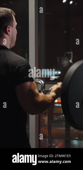 Vertical Screen: Muscular man in black sportswear standing against ...