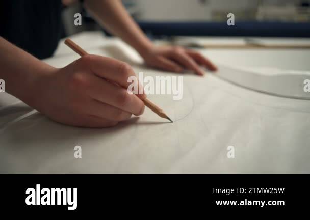Seamstress accurately drawing beautiful line by hands on white paper ...