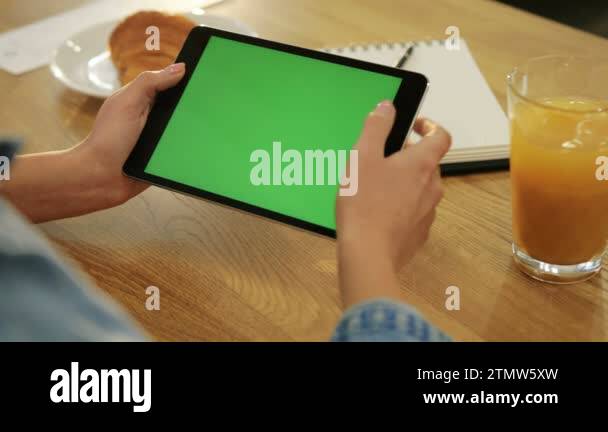 Close-up of womans hands scrolling down page on tablet with green ...