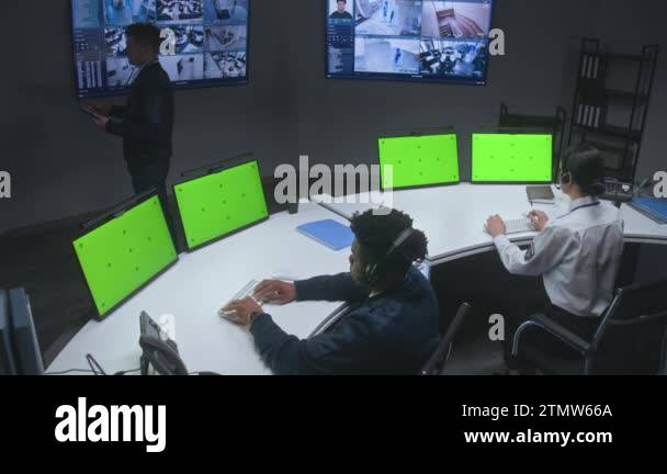 Multiracial officers control security cameras. Workers in monitoring ...