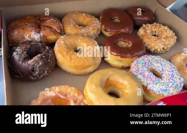 Large, open box of Tim Hortons donuts in contrasted light, with a ...