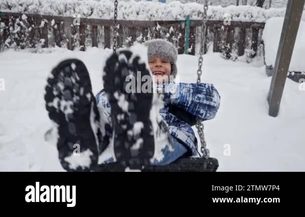 Slow motion of cute smiling boy riding on the swing at playground ...