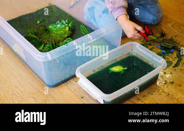 Little girl playing in handmade swamp of green-dyed chia seeds with ...