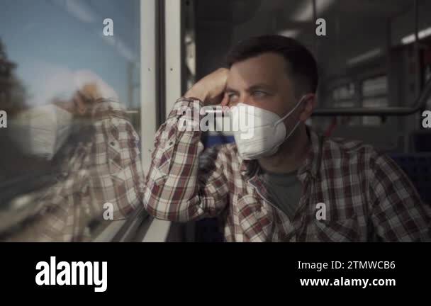 Sad, tired man in mask sitting by window on suburban train in Germany ...
