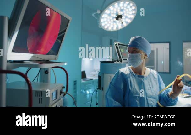 Young female nurse looking at the monitor during plastic surgery ...
