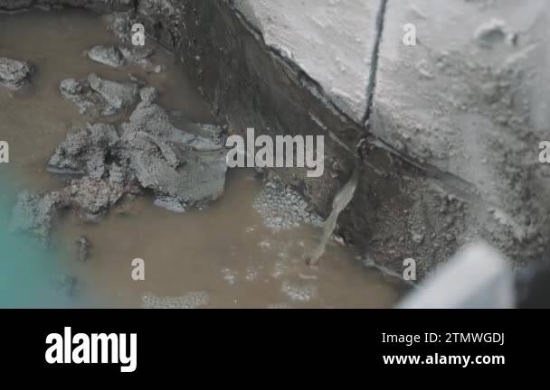 Dirty water pouring through slit in concrete to puddle Stock Video ...