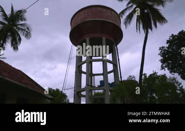 A low-angle view of a water tower in a small Indian village. old water ...