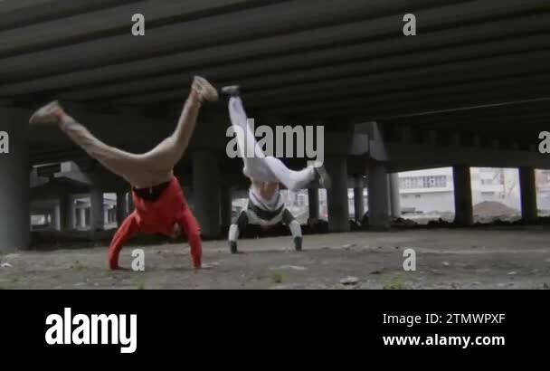 Two young men performing cartwheels and parkour side flips together ...