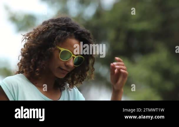 Cute biracial girl making eye-contact by putting down sunglasses while ...