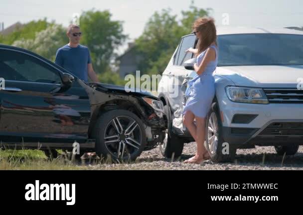 Angry woman and man drivers of heavily damaged vehicles arguing who is ...