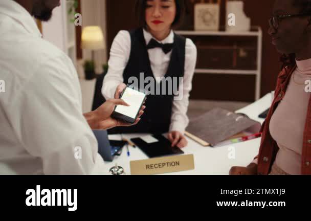 Receptionist using POS payment system to validate card purchase of ...