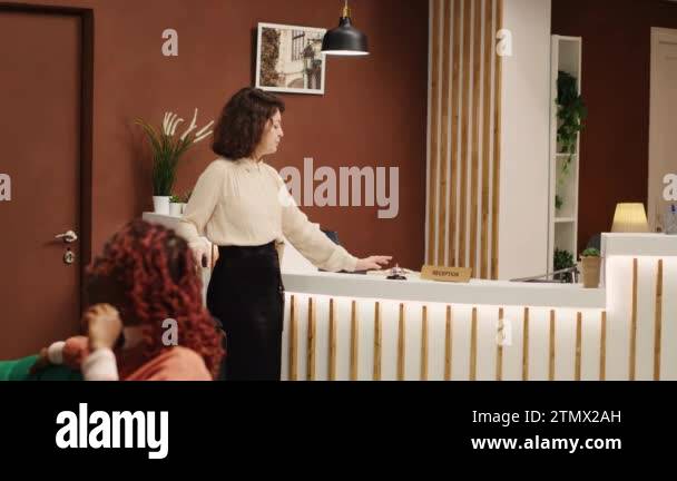 Friendly hotel personnel helping guest with room booking check in ...