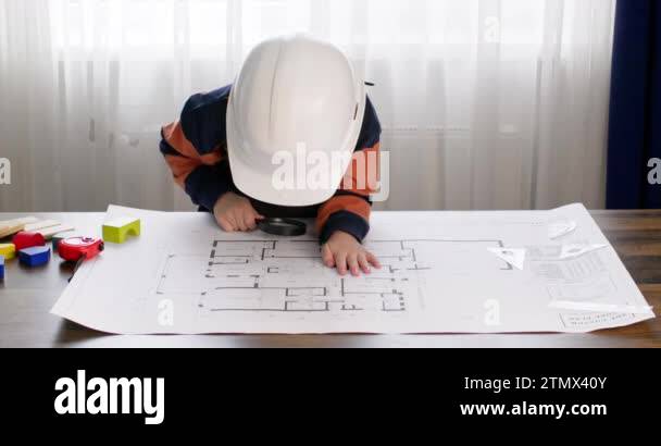Attentive preschooler in white helmet looks with magnifying glass at ...