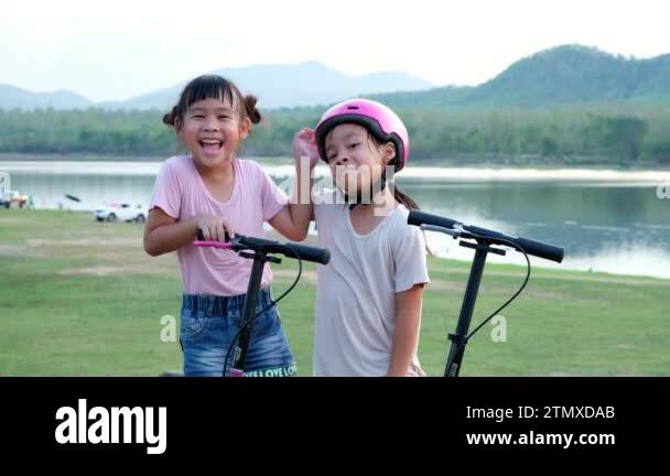 Two cute little girls smiling and posing together in summer garden ...