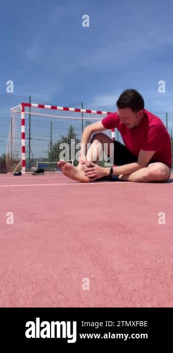 Sprain twisted ankle. Futsal sport injury. Male touching foot in pain ...