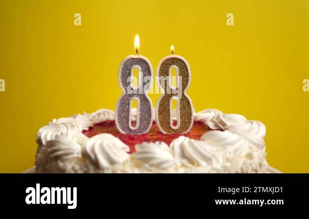 A candle in the form of the number 88, stuck in a holiday cake, is ...