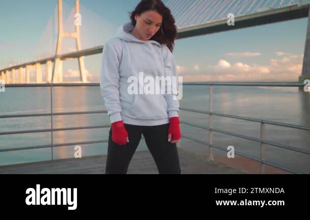 Boxer woman putting hood, looking camera and taking fighting pose ...