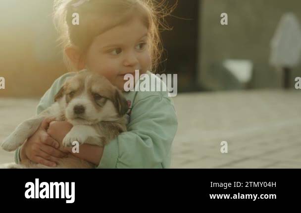 Cute baby girl smiling from pleasure, carrying little baby dog ...