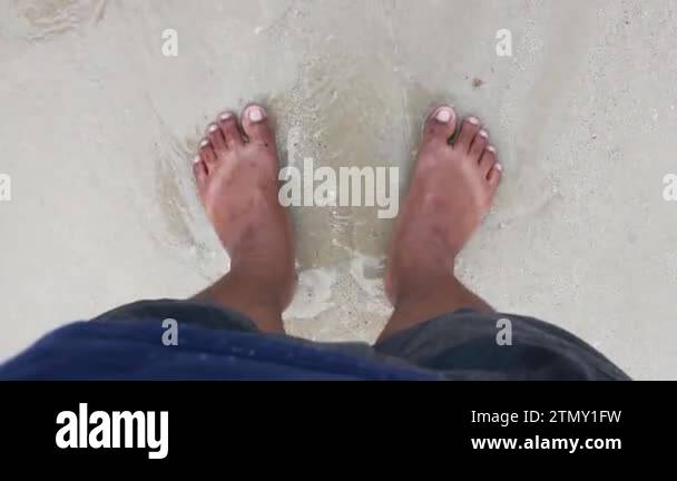 a tourist is standing on the beach and feeling the beach waves with his ...