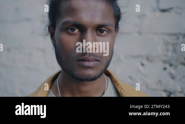 Close-up portrait of serious Indian person looking at camera then ...
