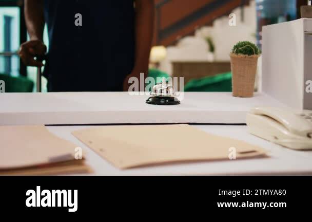 Male tourist ringing service bell at front desk, asking for assistance ...