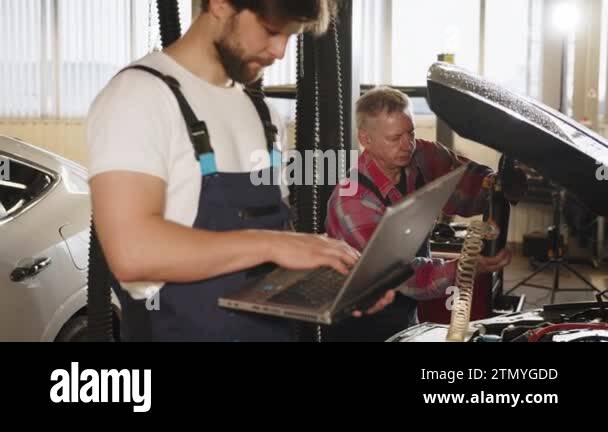 Engineer with laptop makes computer diagnostics of the car engine in ...