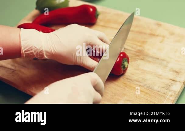 Male hand chop red sweet pepper in half with sharp knife. Wet pepper in ...