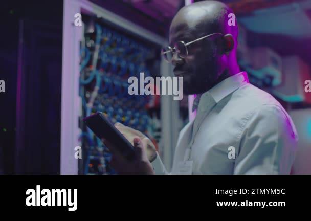 African American IT engineer working on tablet and checking server in ...