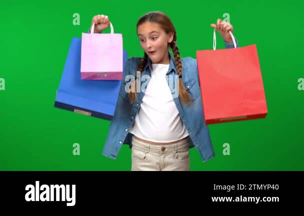 Satisfied stylish teen girl raising shopping bags looking at camera ...