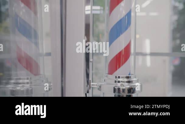 Close-up of barbers pole spinning against glass wall background of ...