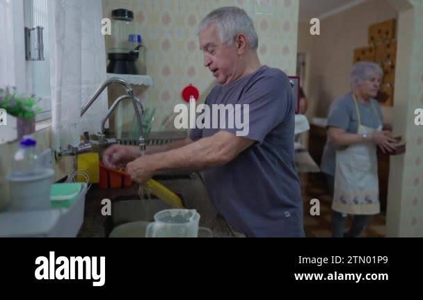 Senior man washing dishes by kitchen sink, candid everyday domestic ...