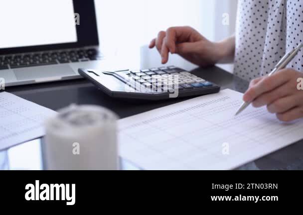 Two accountants use a calculator and laptop computer for counting taxes ...