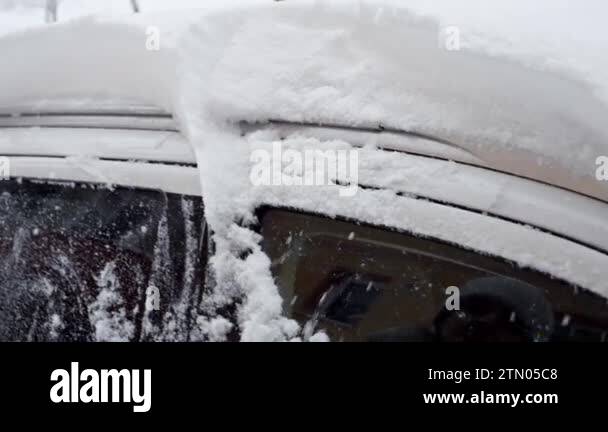 Clearing snow off of her car using a brush on a snowy morning. Concept ...