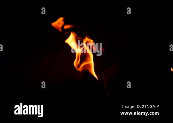 Fire burning slowly from a spot in darkness breeze effect on flame ...