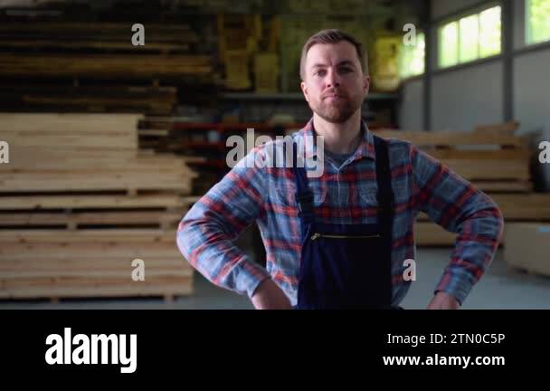 Young male worker in timber lumber warehouse. Wooden boards, lumber ...