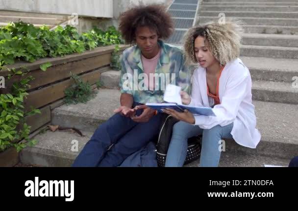 Multiracial group of gen z college students talk and laugh sitting on ...