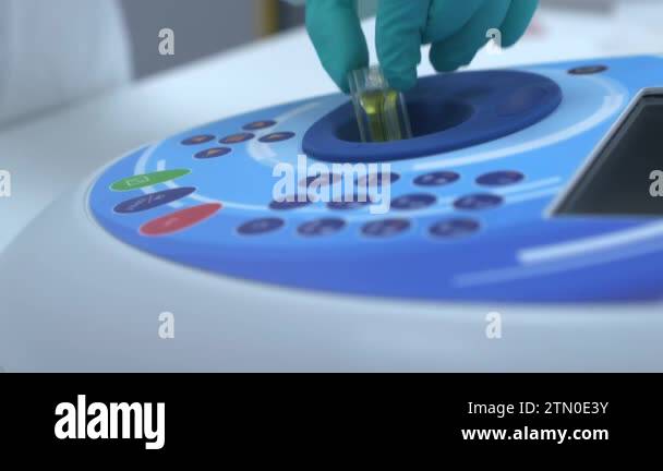 Close up woman hand inserts a cuvette with the yellow solution into the ...