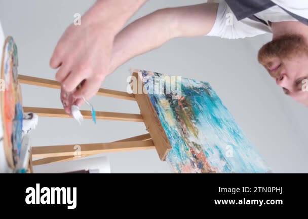 Vertical video of a professional artist painting a picture on a white ...