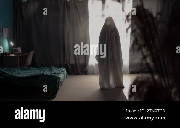 Creepy ghost figure in mysterious window, bedroom interior at night. House ghost concept Stock ...