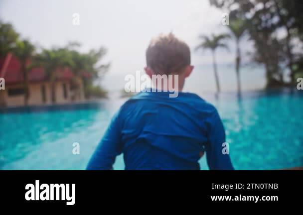 A back view shot of a boy wearing a blue rash guard running towards ...