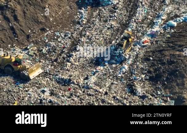 Waste managment concept. Large landfill site with bulldozers burying ...
