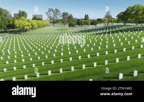 Drone flying above scenic green field with straight rows white grave ...