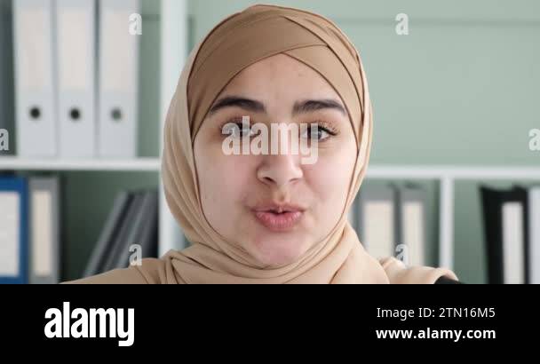 Close-up portrait of an Arab woman wearing a hijab engaged in a ...
