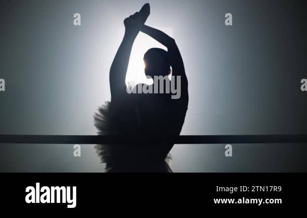 Ballerina stretches near the ballet barre in the dance hall ...